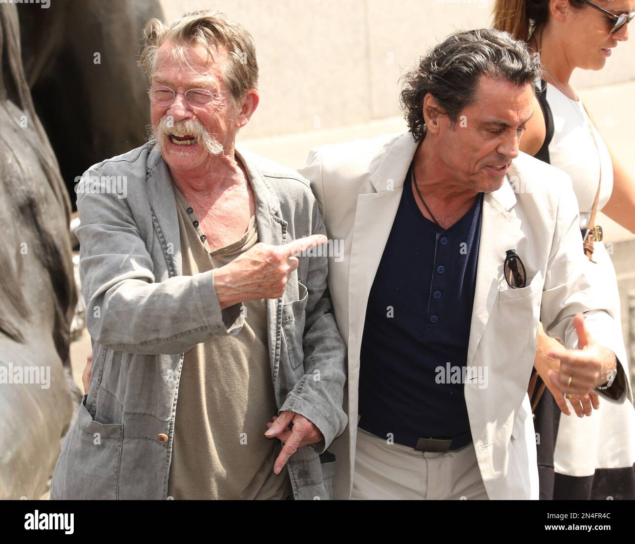 John Hurt and Ian McShane joke around in front of one of the lion statues by Nelson's column on ...