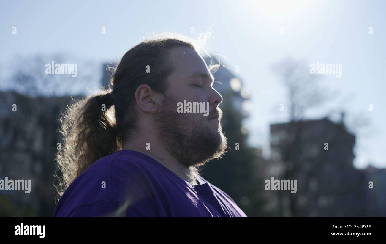 One meditative overweight young man in contemplation outside. Close up ...