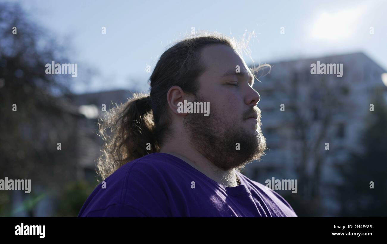 One meditative overweight young man in contemplation outside. Close up ...