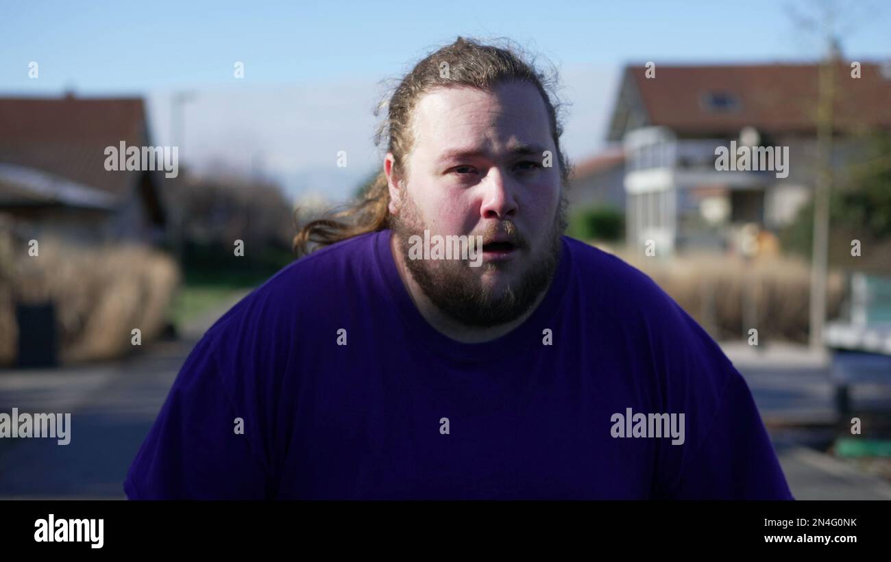 One exhausted overweight young man having chest pains standing outside ...
