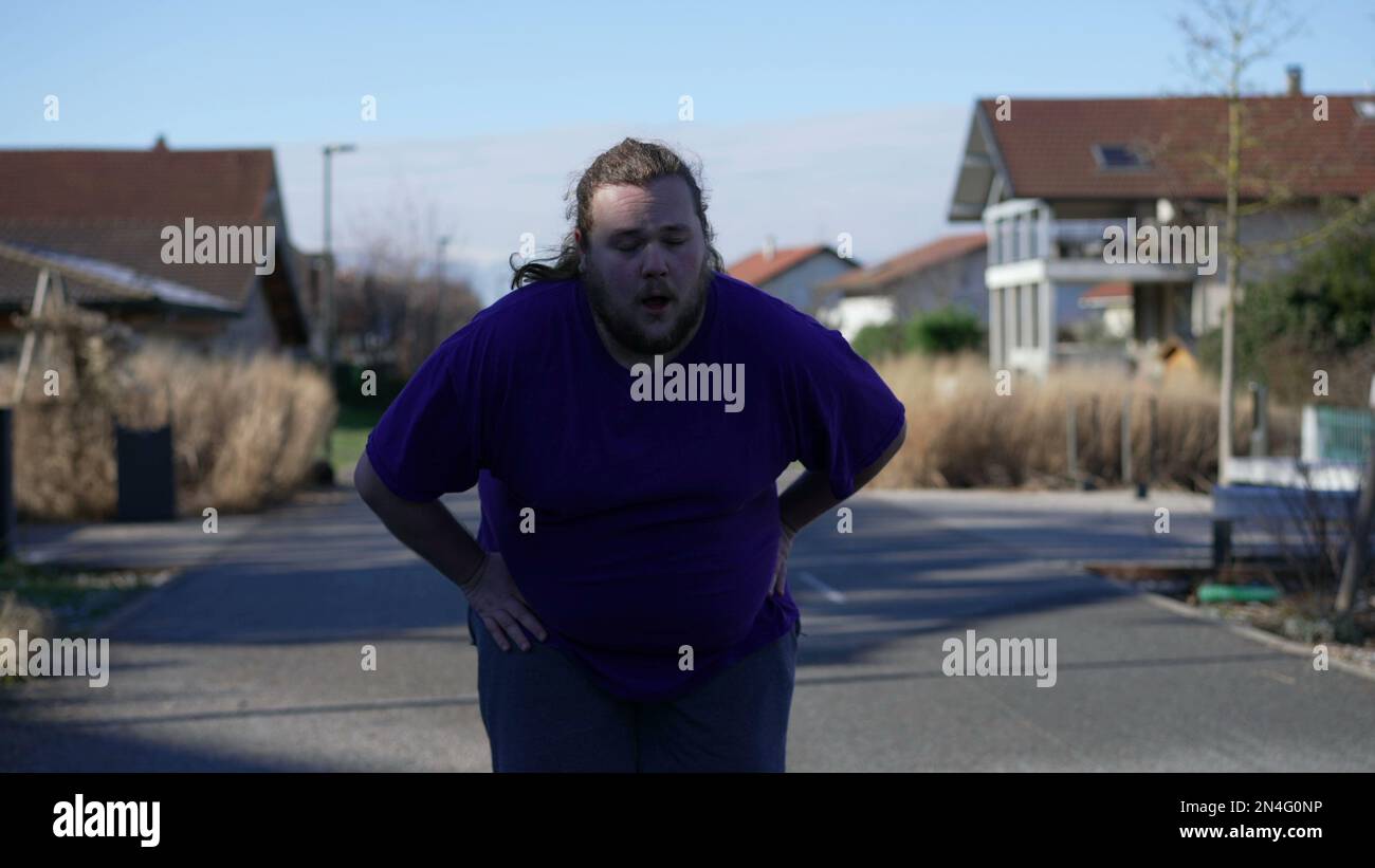 One exhausted overweight young man having chest pains standing outside ...