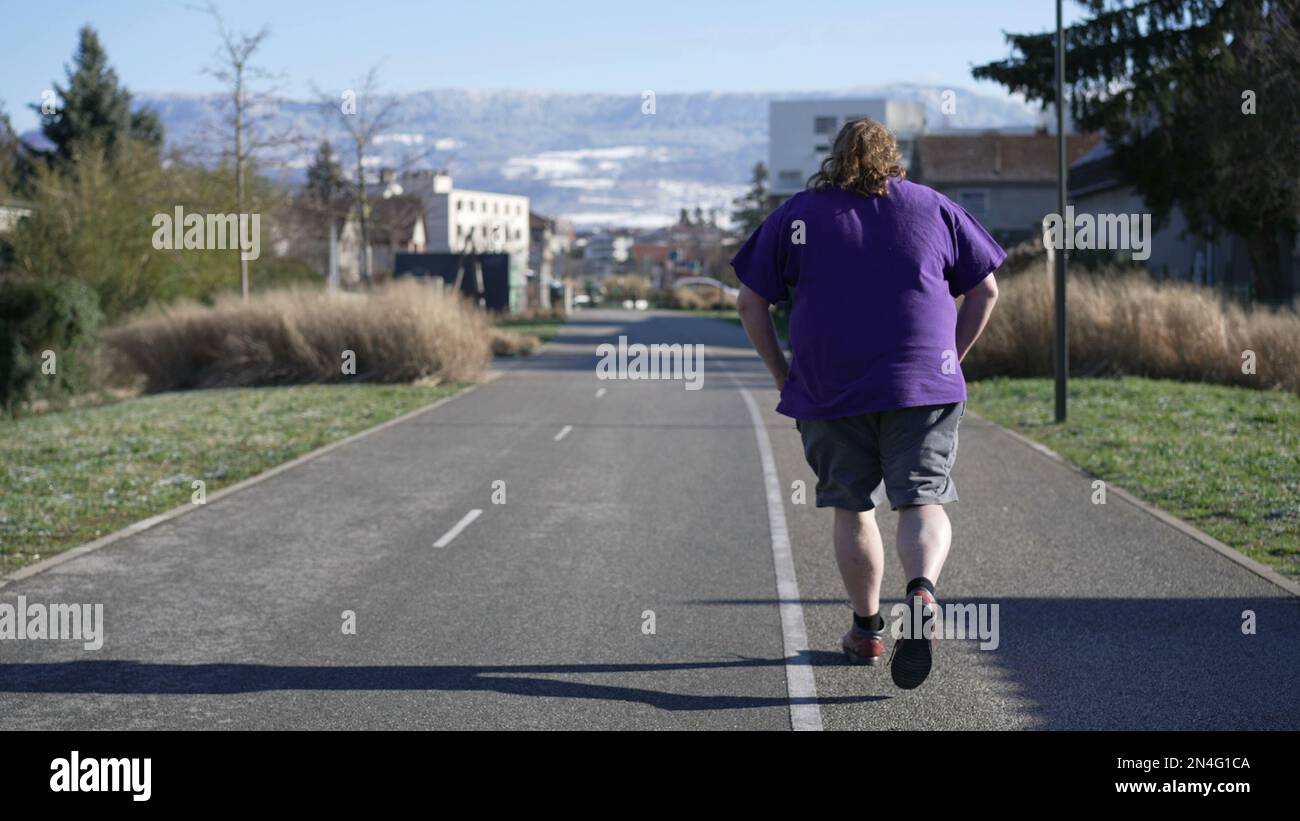 Back of One young overweight man jogging outdoors. Tracking shot of a ...