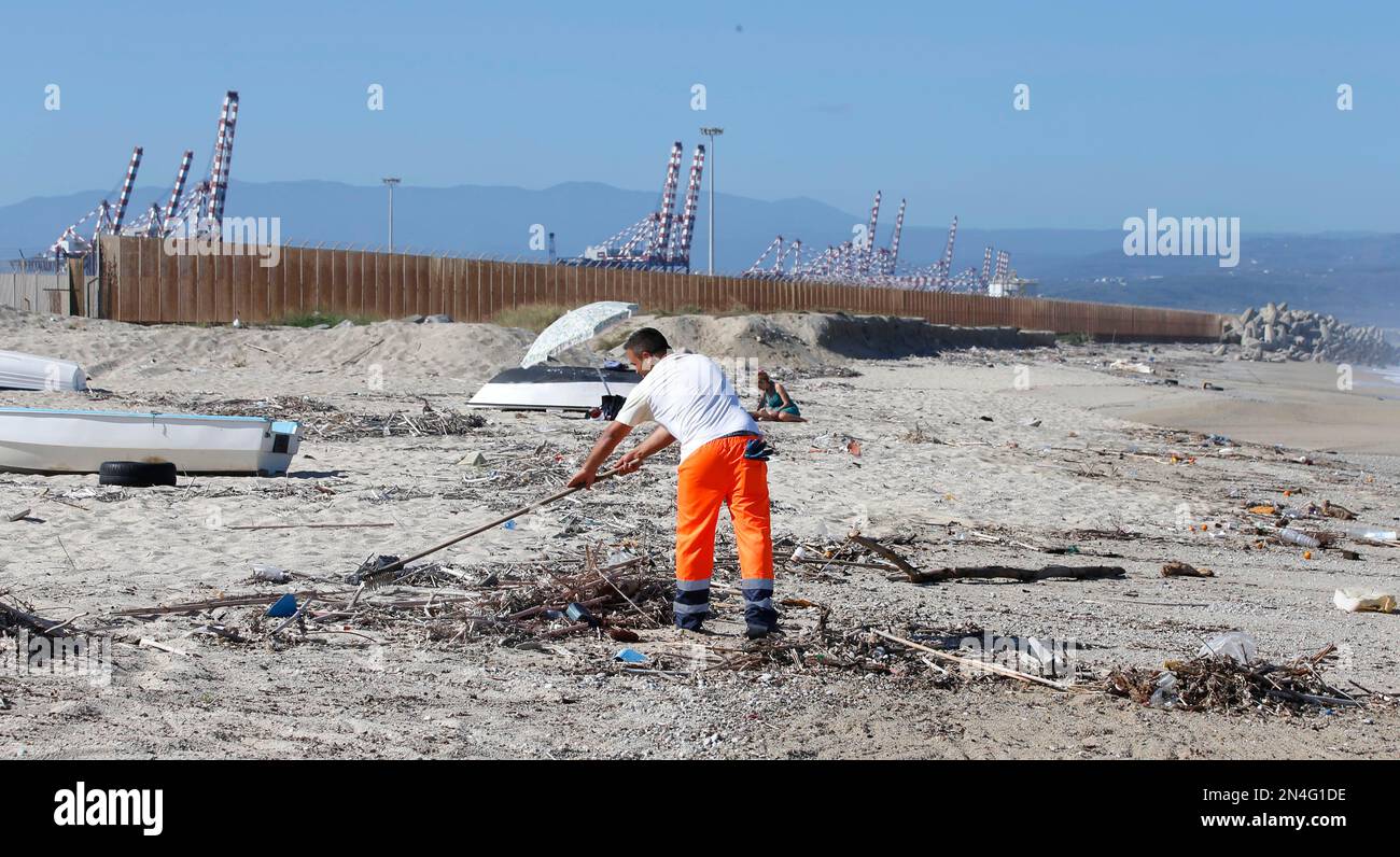 A garbage worker cleans the San Ferdinando beach, next to the Gioia ...