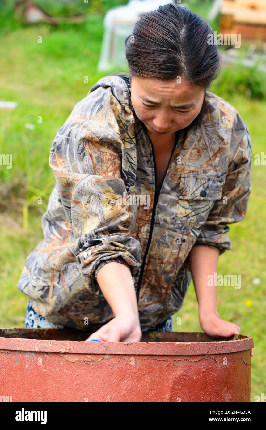Yakut Asian girl tiredly cleans and washes the iron tank to collect ...