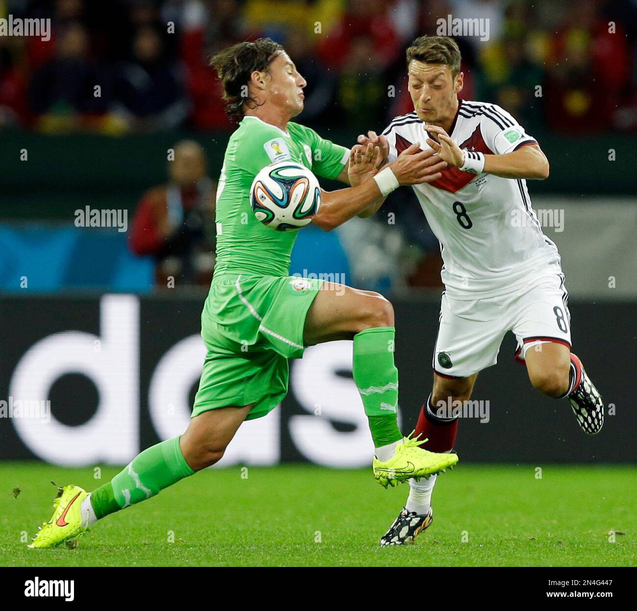 Algeria's Mehdi Mostefa, left, pushes off Germany's Mesut Ozil to stop ...