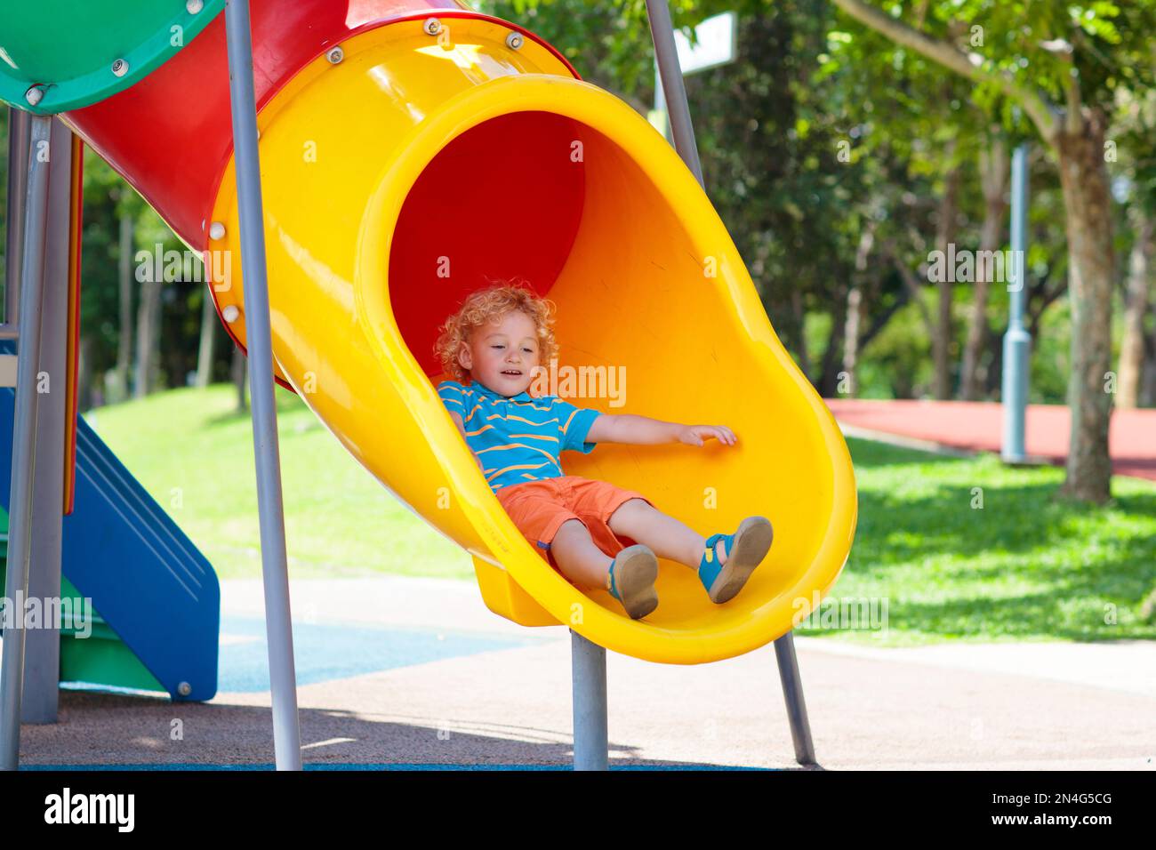 Kids climbing and sliding on outdoor playground. Children play in sunny ...