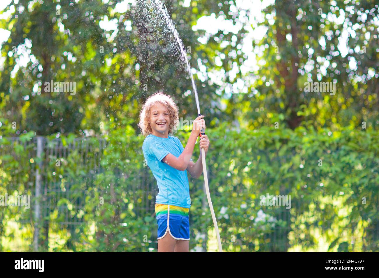 Kids play with water sprinkle hose. Summer garden outdoor fun for ...