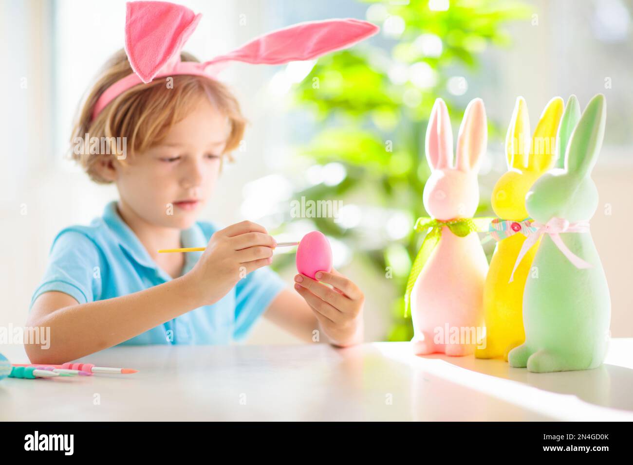 Kids dyeing Easter eggs. Children in bunny ears dye colorful egg for ...