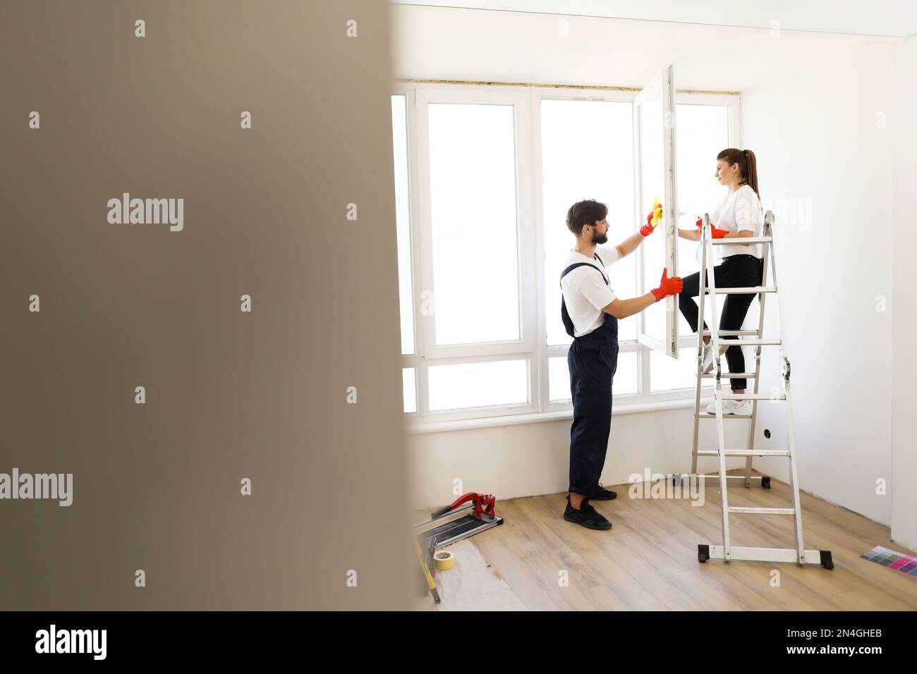 Beautiful caucasian couple wife and husband cleaning window together in ...