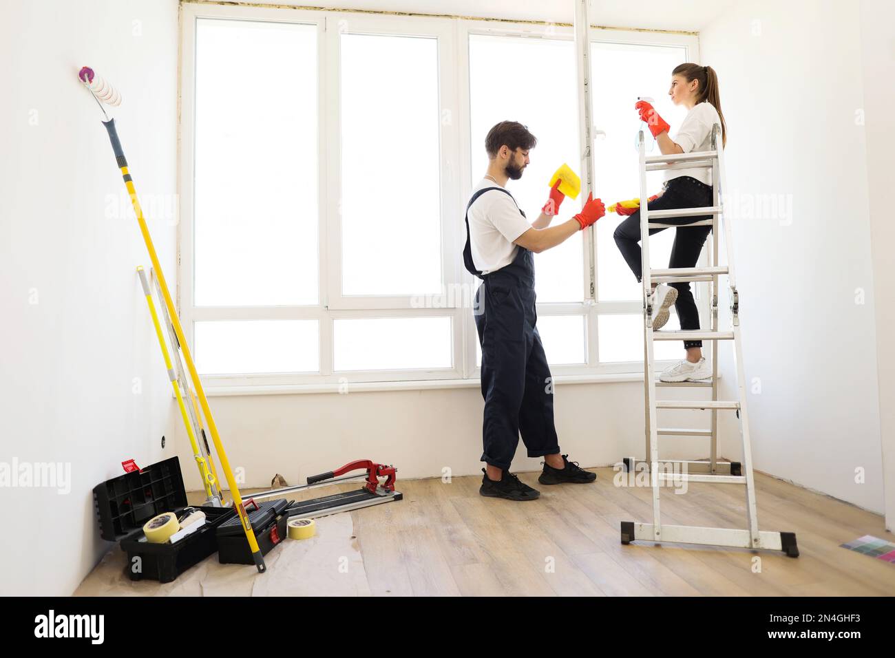Young family of two, pretty woman sitting on ladder and bearded man ...