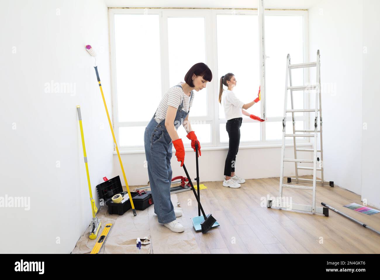 Young beautiful women cleaning up new apartment after renovation. One ...