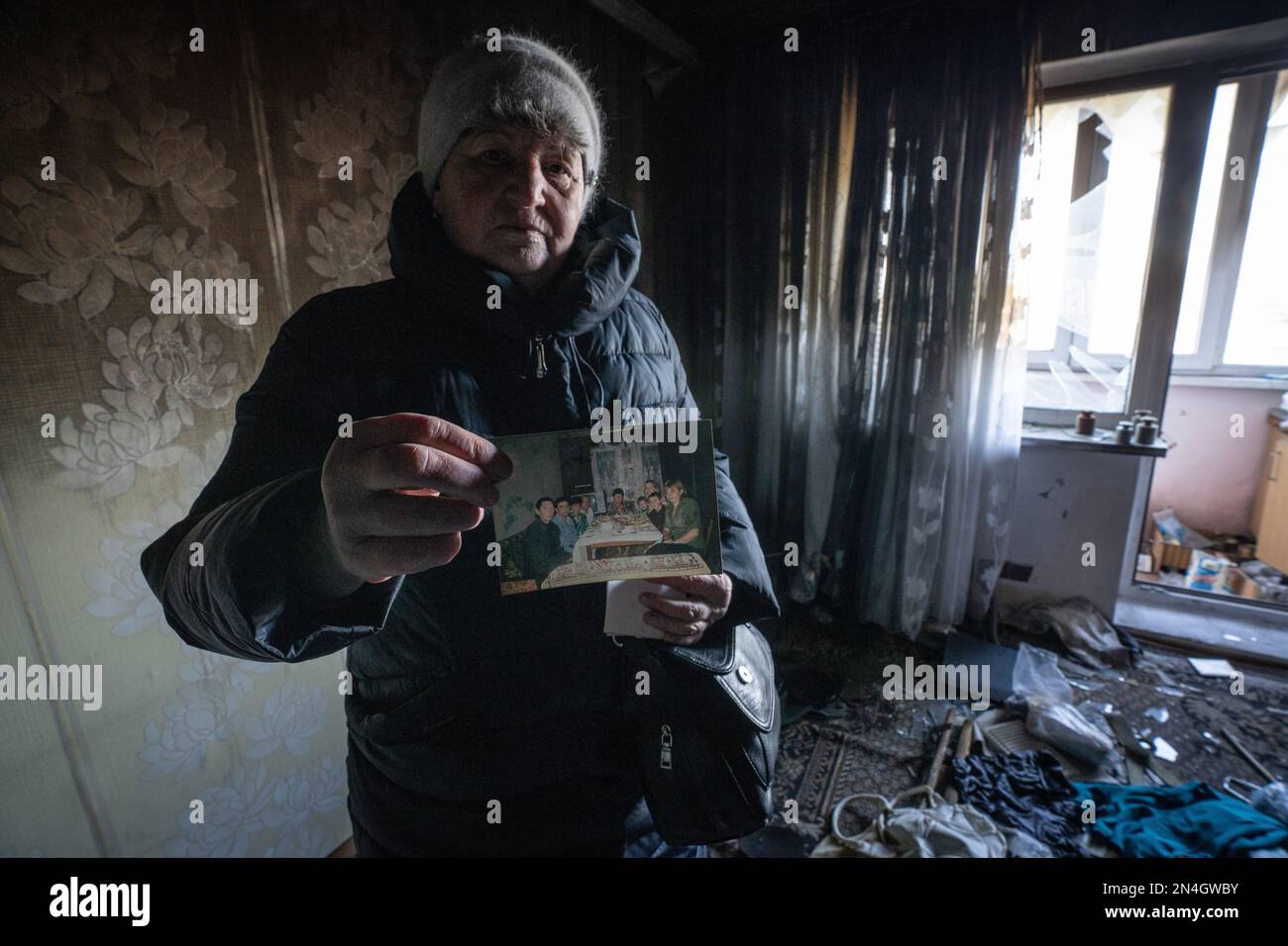Irpin, Ukraine - February 8, 2023: An owner of damaged house shows picture of the residence ...