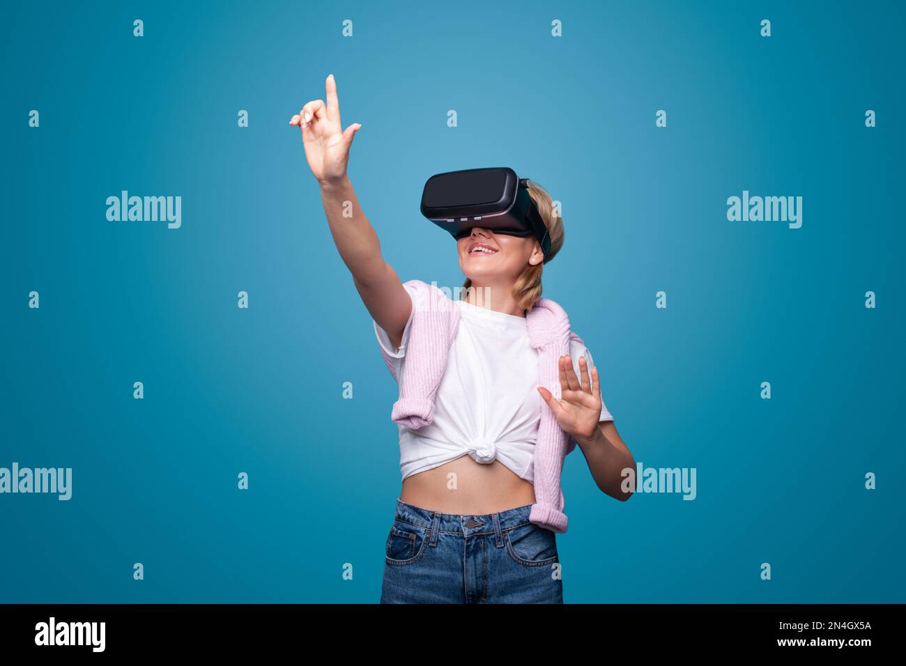 Happy excited woman in VR headset exploring new worlds in videogame isolated over blue ...
