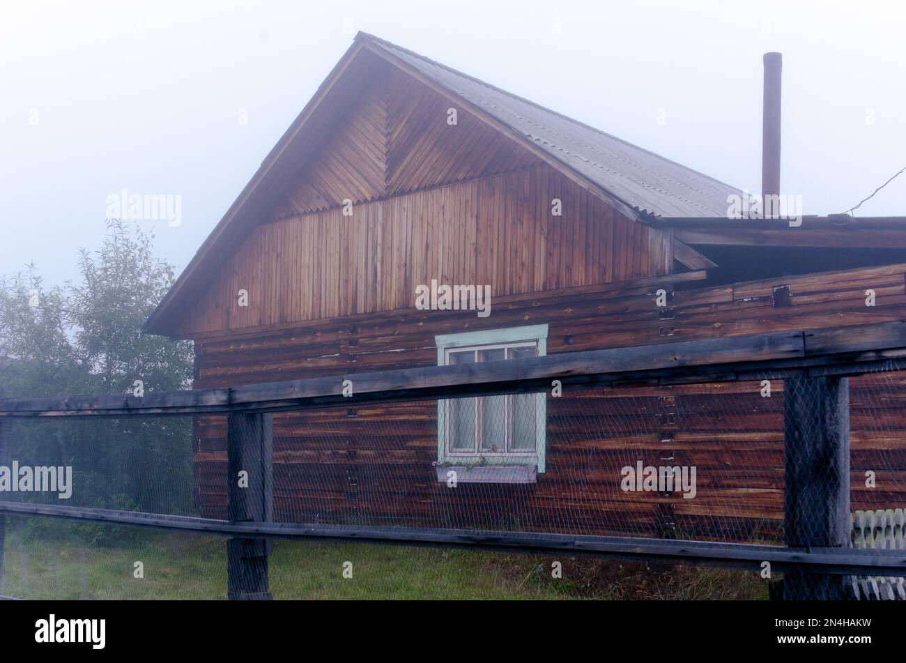 Private Yakut wooden house made of pine log stands in the fog side with ...