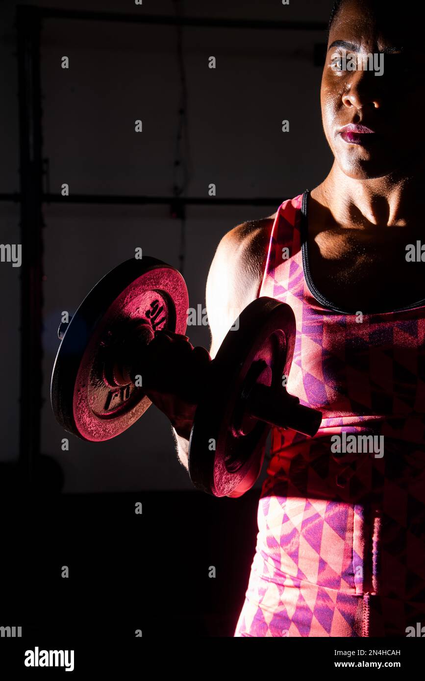 Dramatic portrait of fitness woman doing exercise for arm muscle. Gym ...