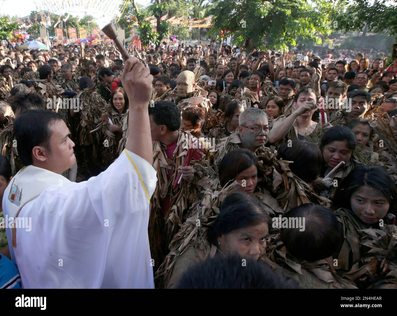 A Roman Catholic priest blesses residents, who are covered in mud and ...