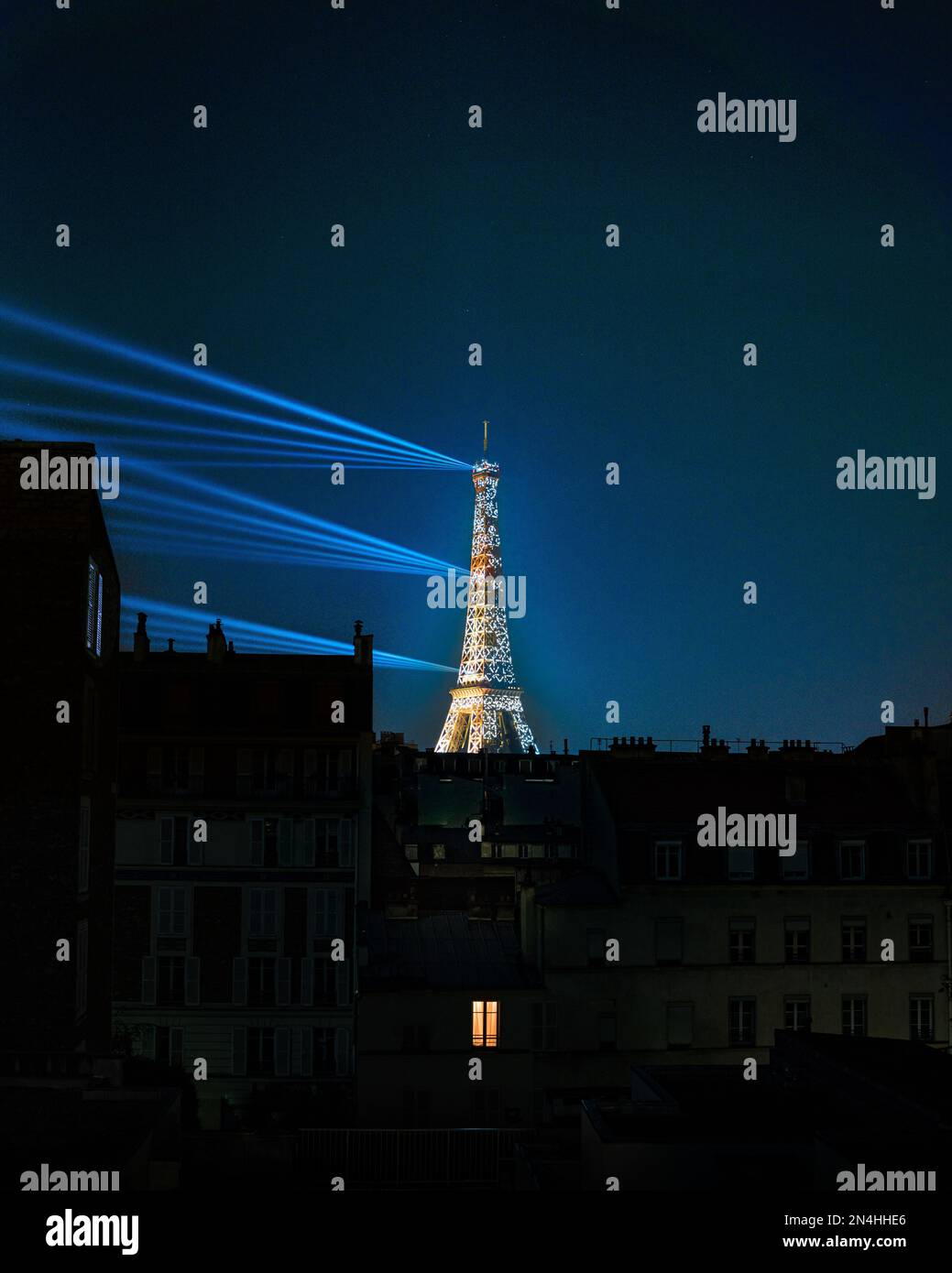 A vertical shot of the Eiffel Tower beaming blue lights in the night ...