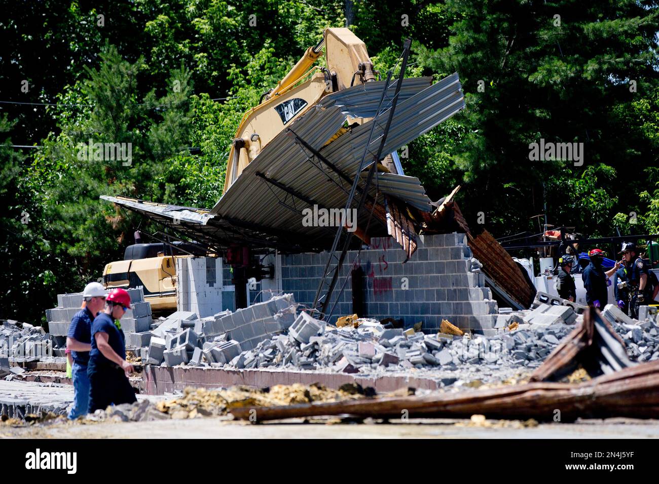 Investigators, left, walk around the scene of a fatal building collapse ...