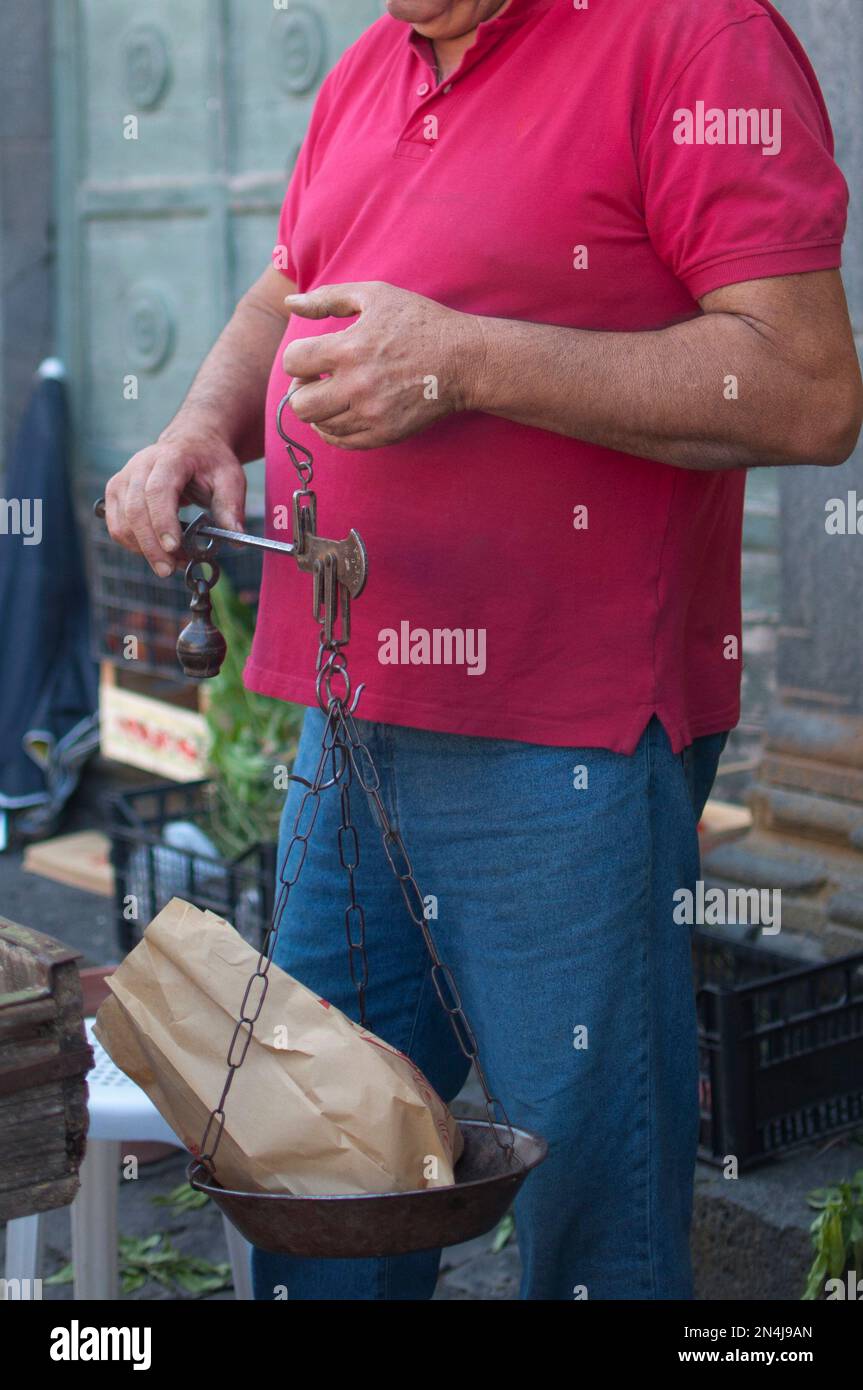 Unrecognizable man using a traditional weighing scale in a street ...
