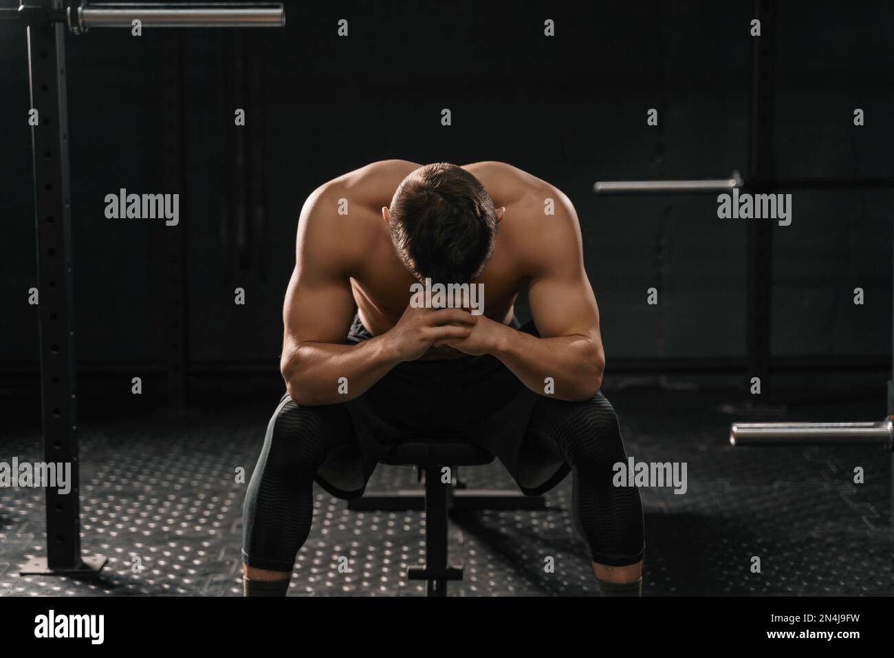 Strong sporty man sitting on gym bench suffering breakdown to overcome ...