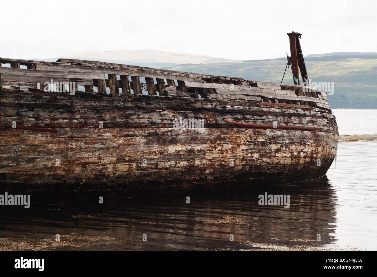The hull of a long wooden ship leaning to one side, decaying and ...