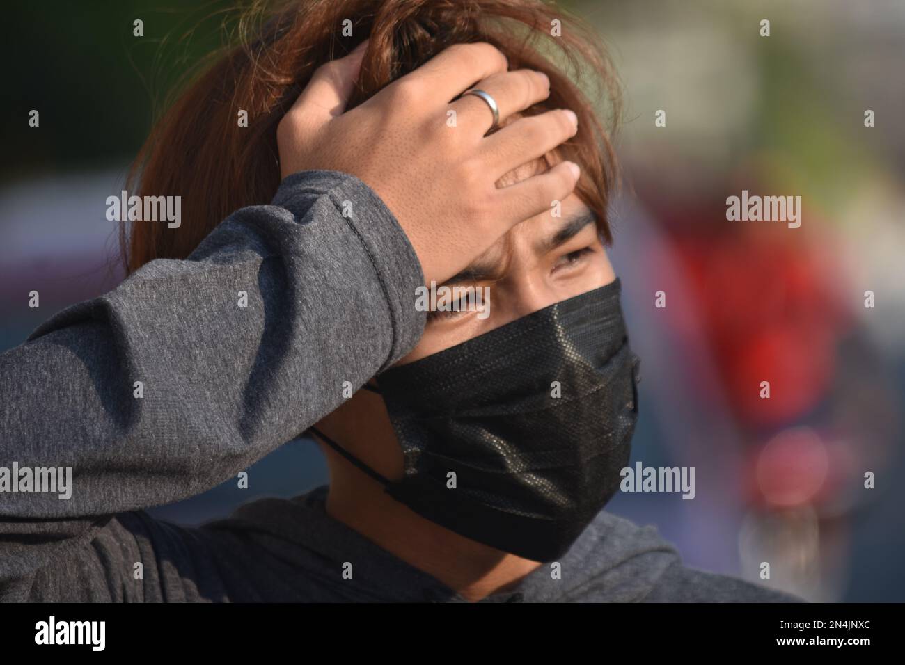 A portrait of a teenage Southeast Asian with brown hair wearing a black ...