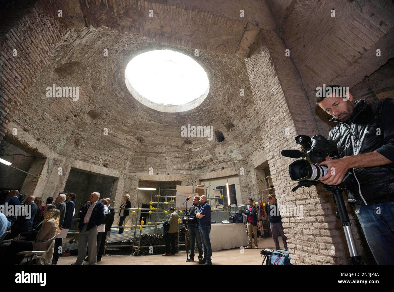 Journalists crowd the octagonal room, surmounted by a dome with a giant ...