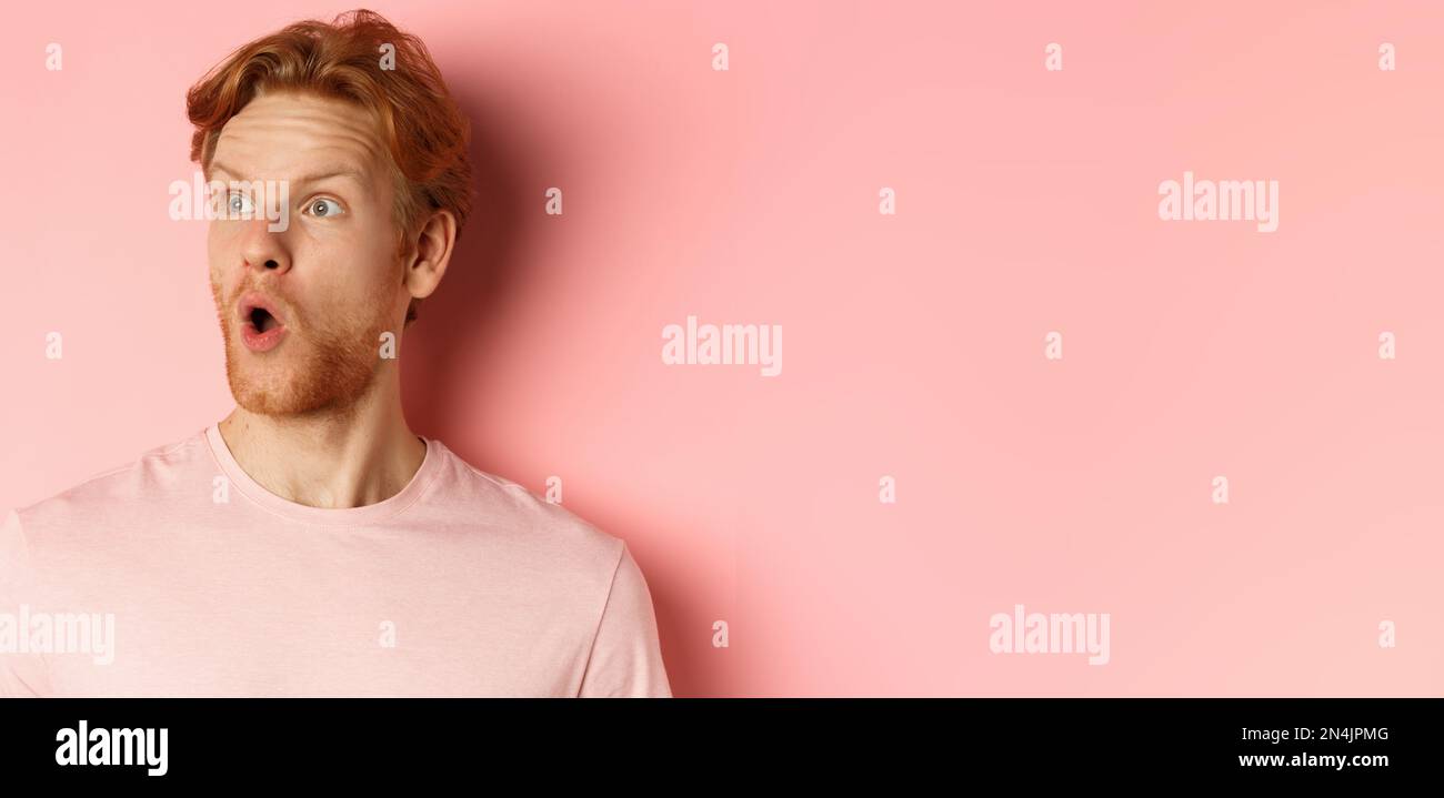 Close up of shocked redhead man with beard, saying wow, looking left ...
