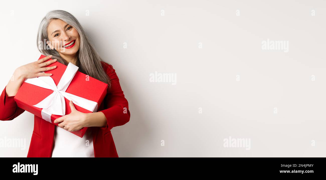 Happy asian grandmother hugging red gift box and smiling grateful ...