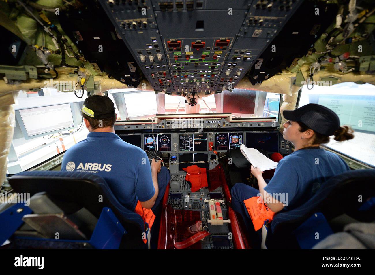 Airbus employees sit in the cockpit of an Airbus A350 XWB , at its ...