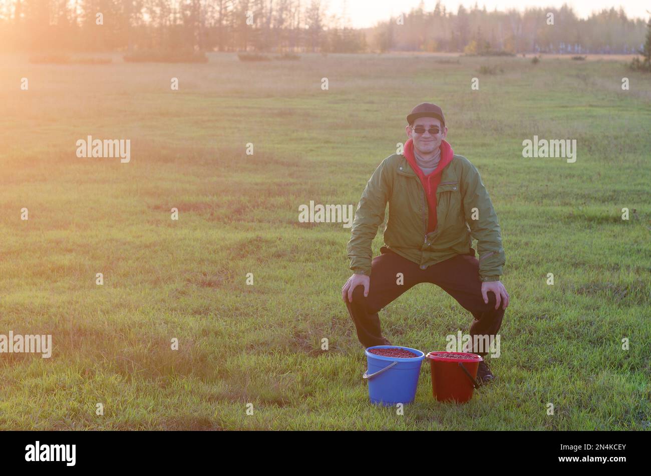 Cheerful man standing with legs apart, smiling at the two buckets with ...