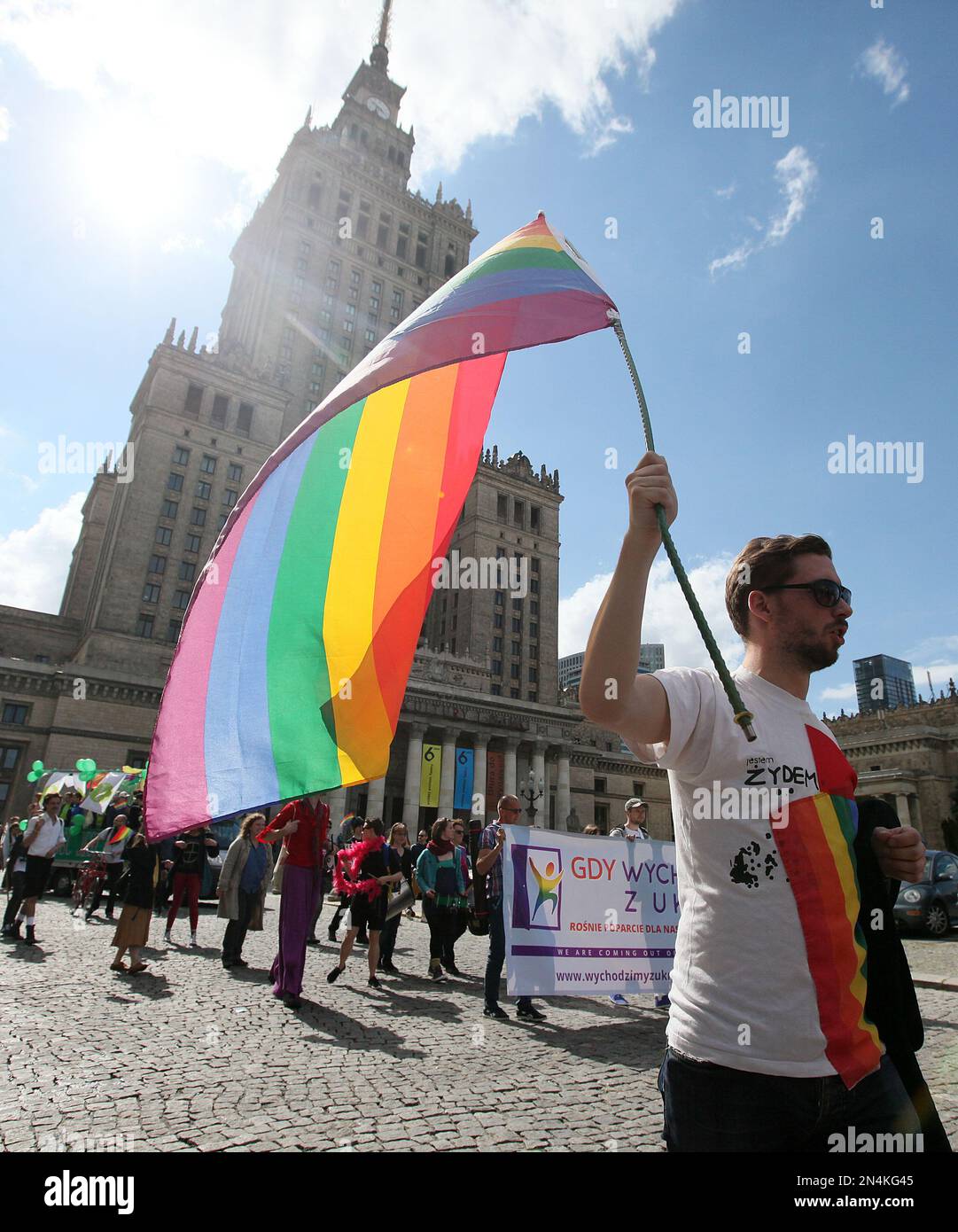 A man carries a multicolor flag as he passes the Polish parliament ...