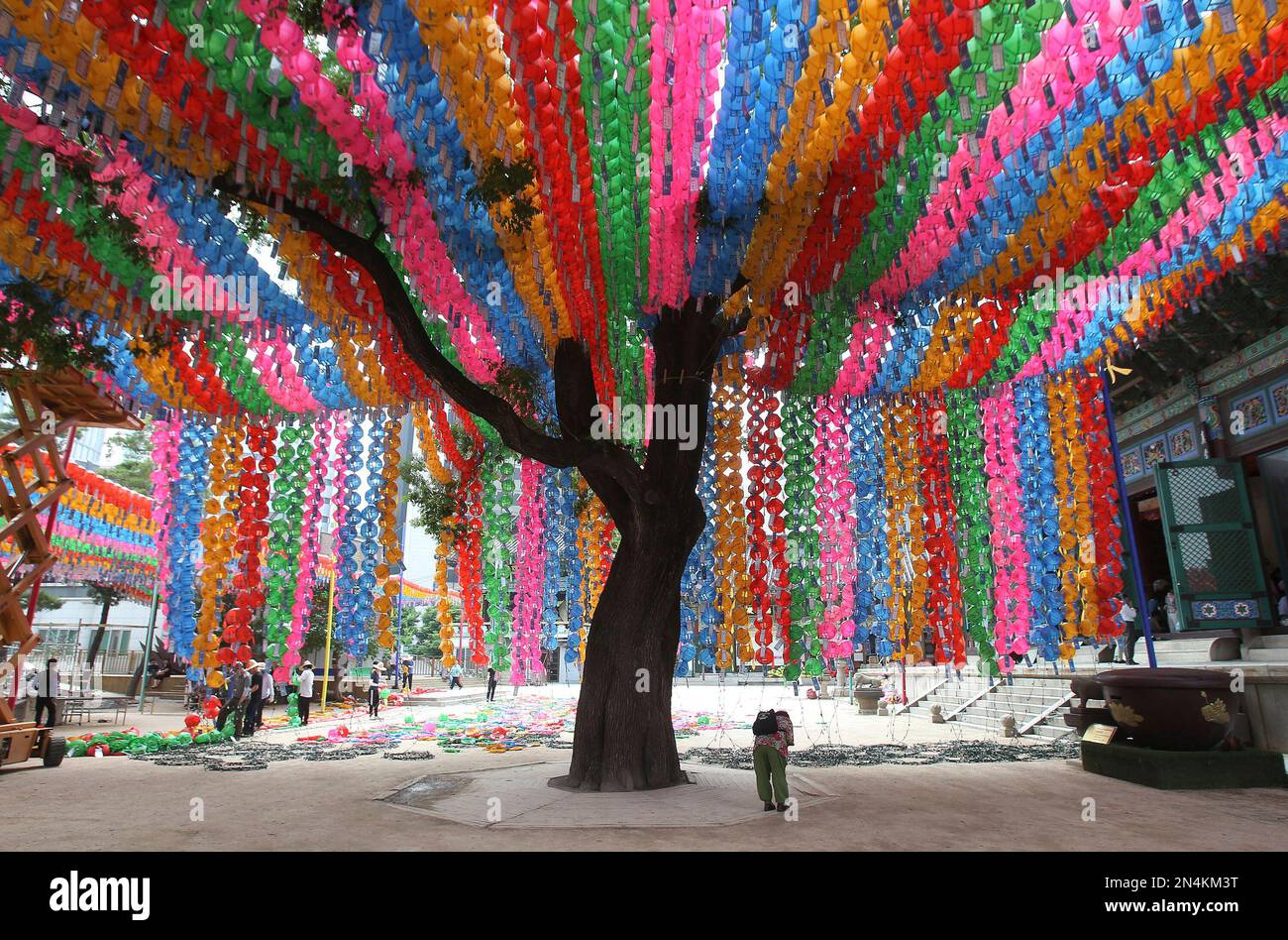 A woman prays as workers prepare to remove lantern decorations after a ...