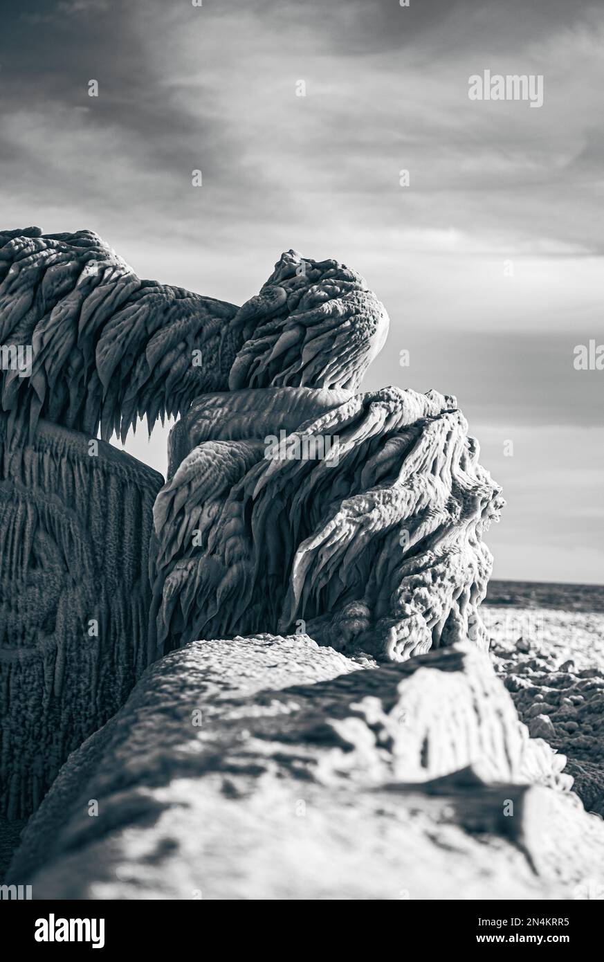An icy landscape featuring a large rock formation with a thick icicle ...