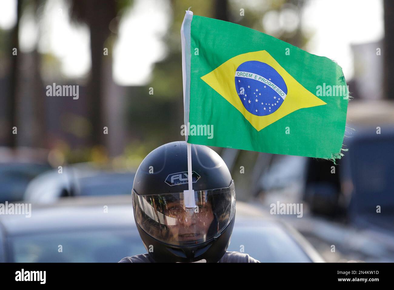 A soccer fan wears a motorcycle helmet with a Brazil national flag in ...