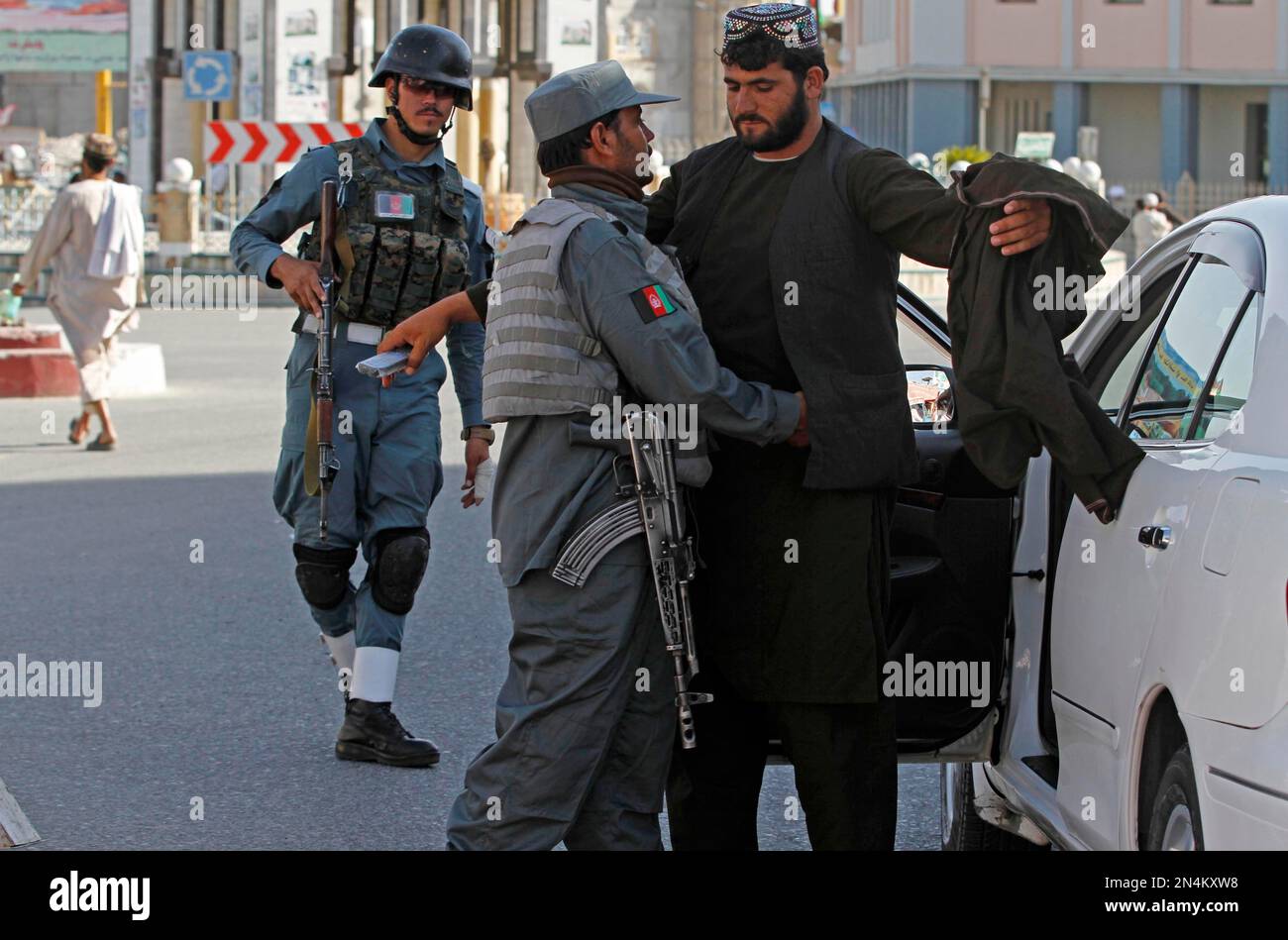 Afghanistan police search a passenger at a checkpoint in Kandahar ...