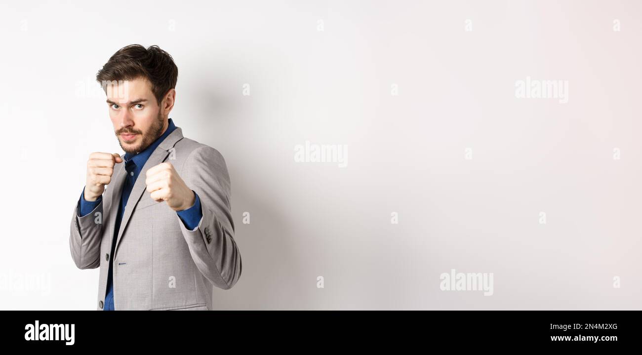 Serious man in suit raising hands in boxer pose, going to fight ...