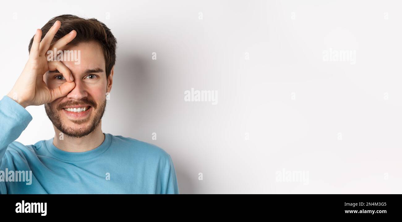 Close up of happy man looking through okay sign and smiling, approve ...