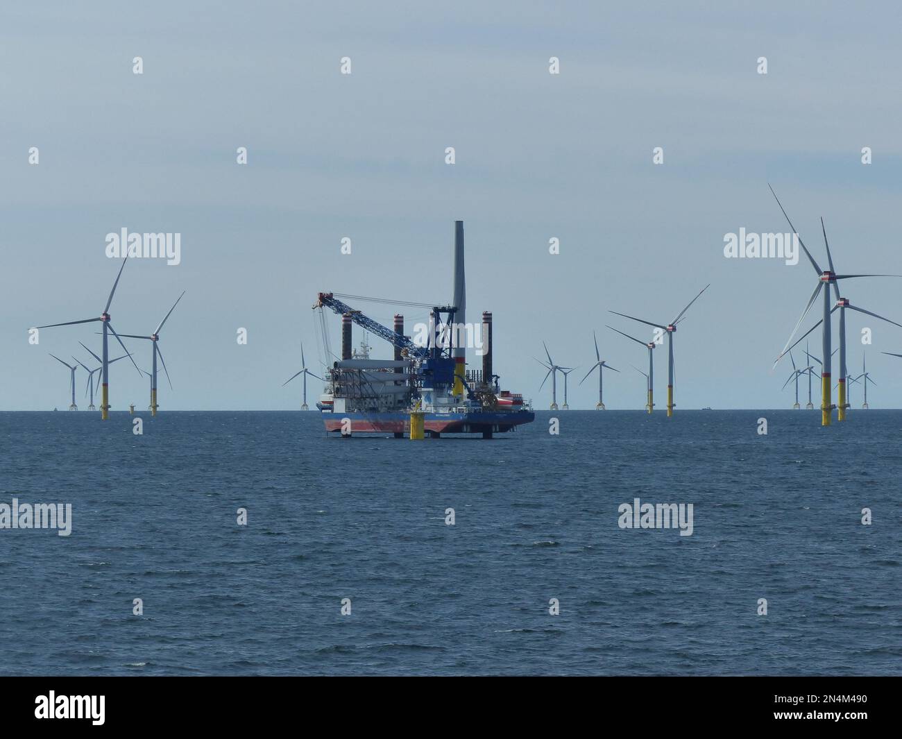 A cargo ship carrying load on the sea surrounded y wind turbines Stock ...