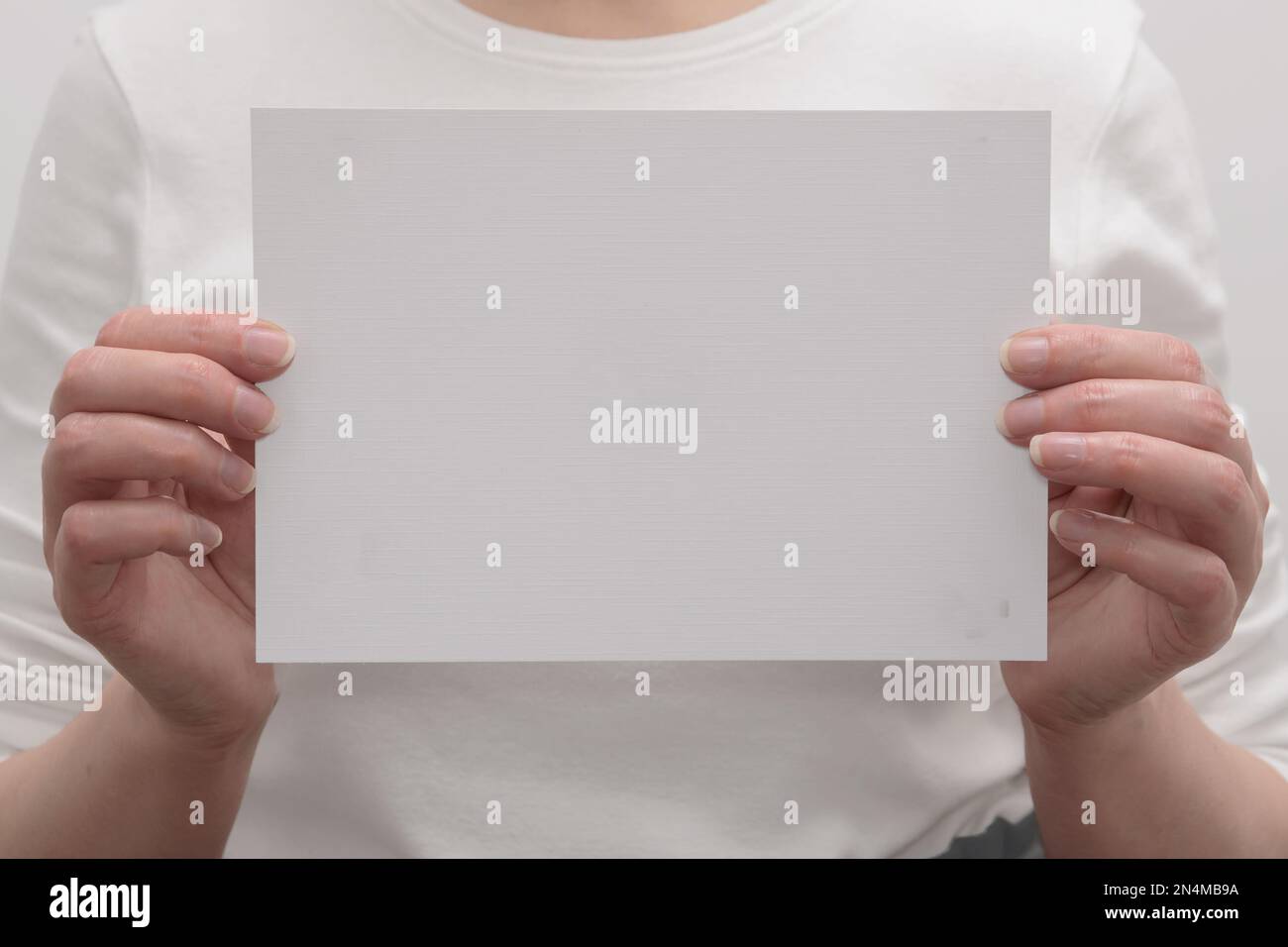 Female hands hold a blank sheet of paper. mockup for agenda or activity ...