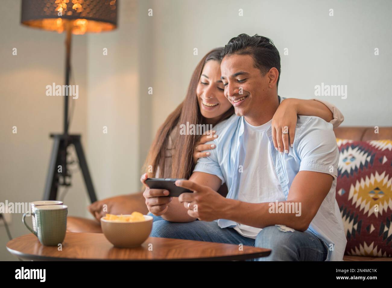Happy young happy couple using smartphone social media apps at home ...