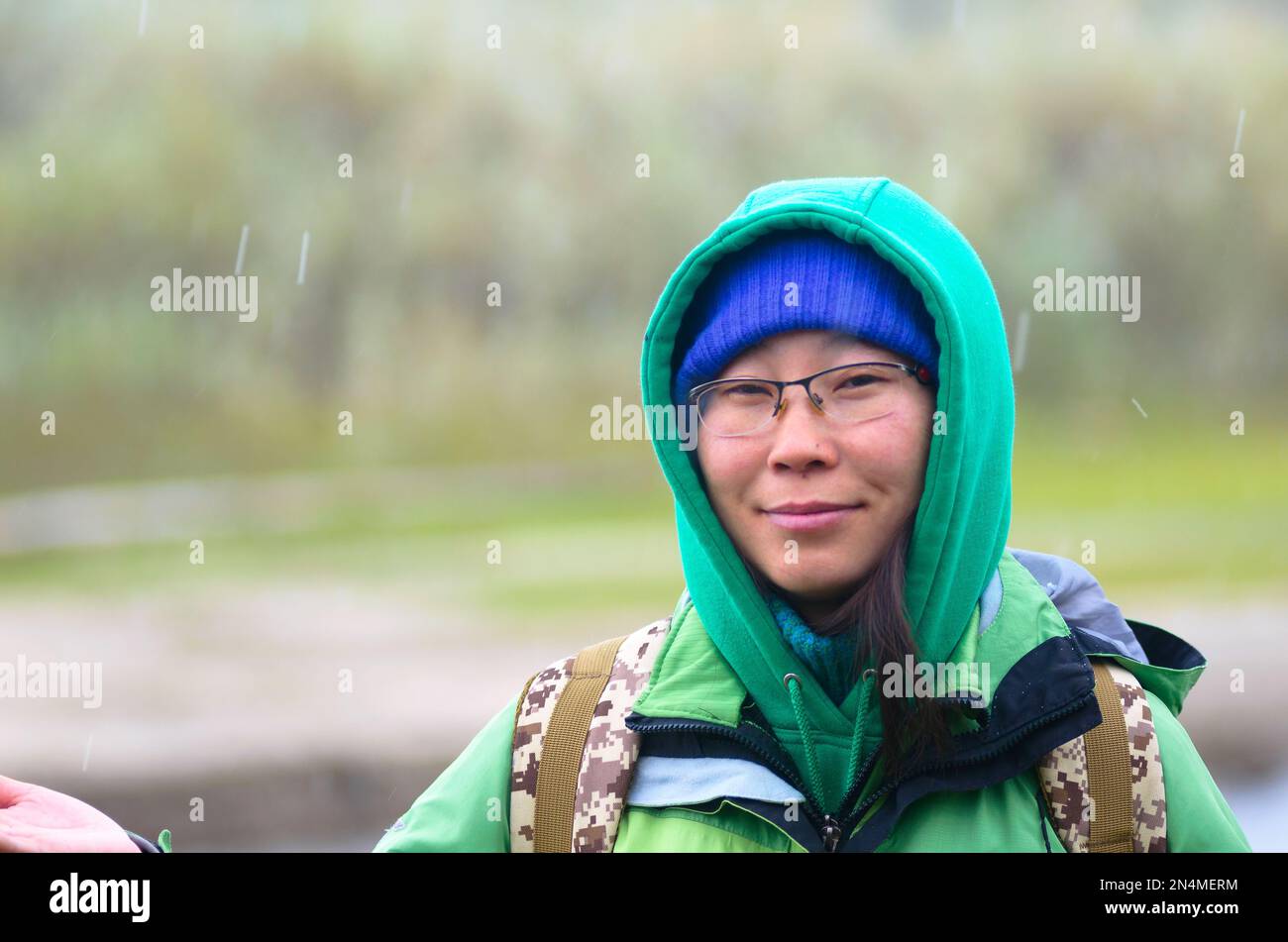 Yakut Asian Girl Tourist In Hat And Hood Smiling With Glasses On The Background Of Snowy Weather
