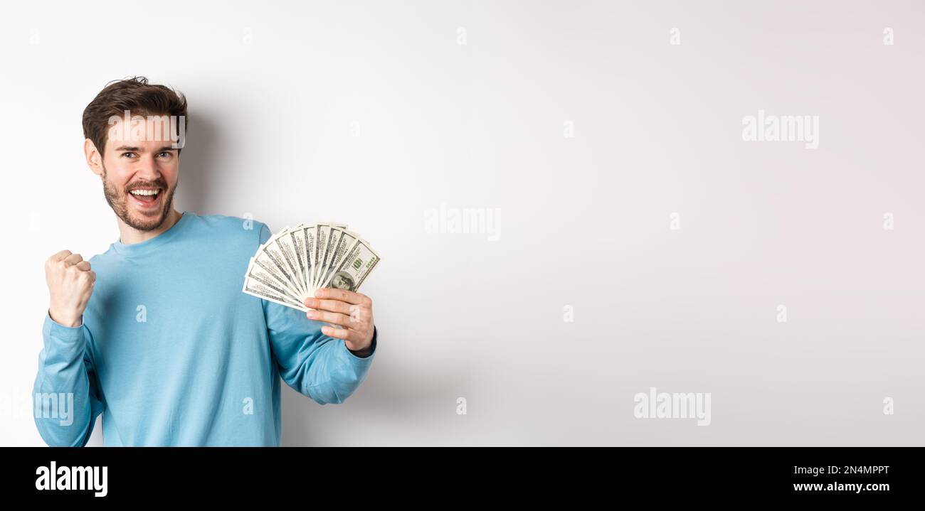 Happy man dancing with money, showing dollars and saying yes with ...