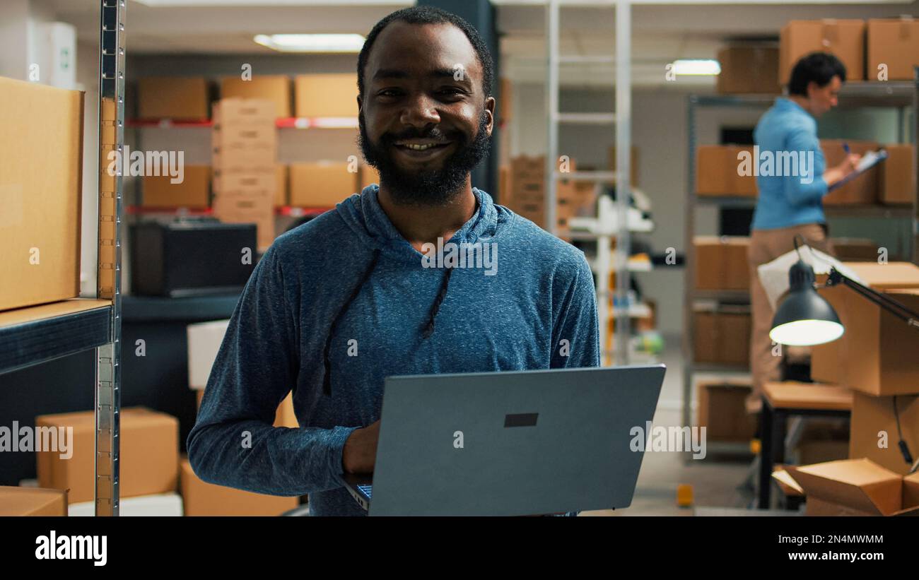 Warehouse employee using laptop to write products information ...