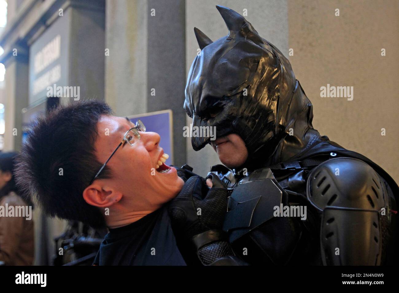 A man, dressed as Batman character, poses for photos with a shopper in ...