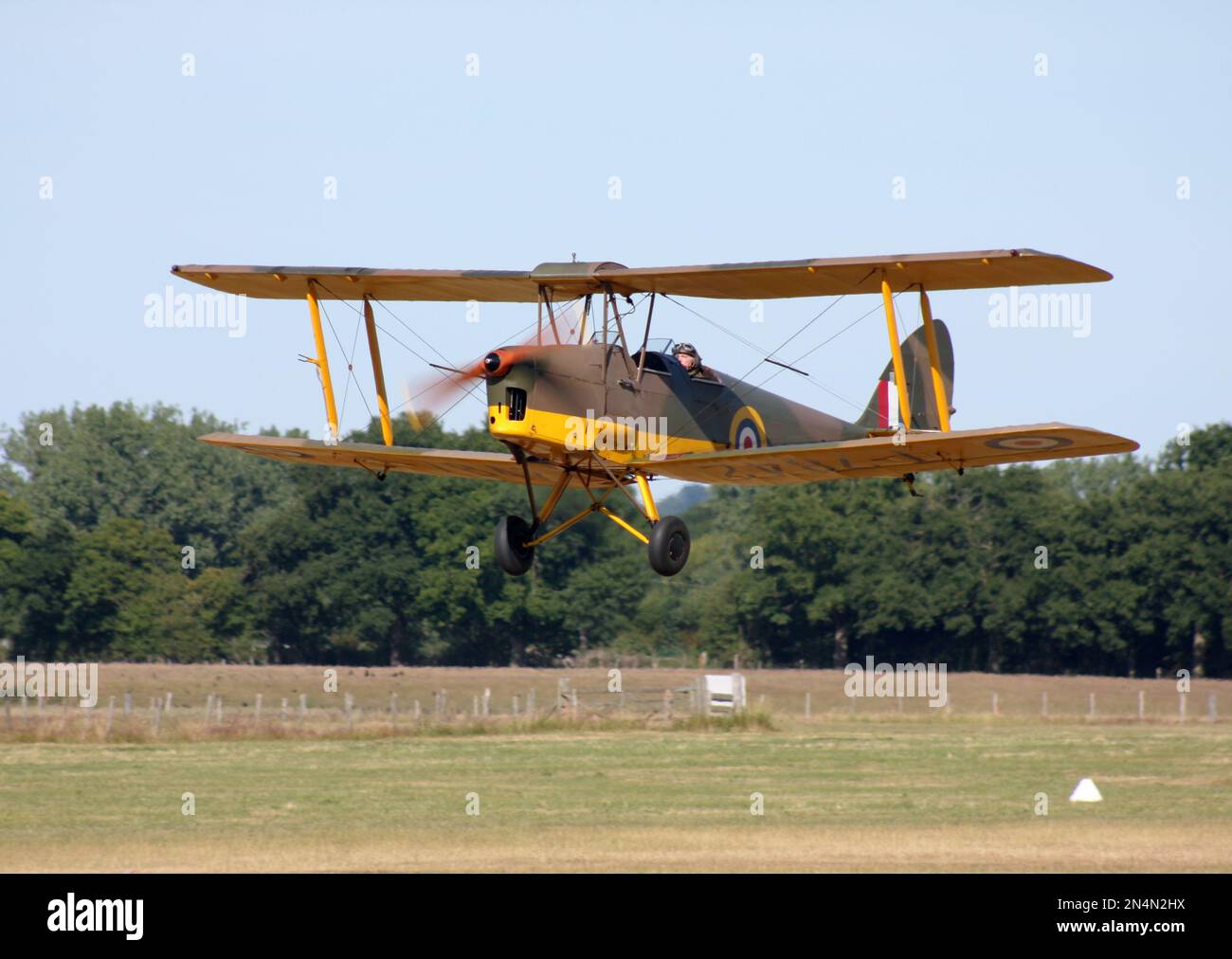 A De Havilland DH-82 Tiger Moth departs Headcorn airfield Kent England ...