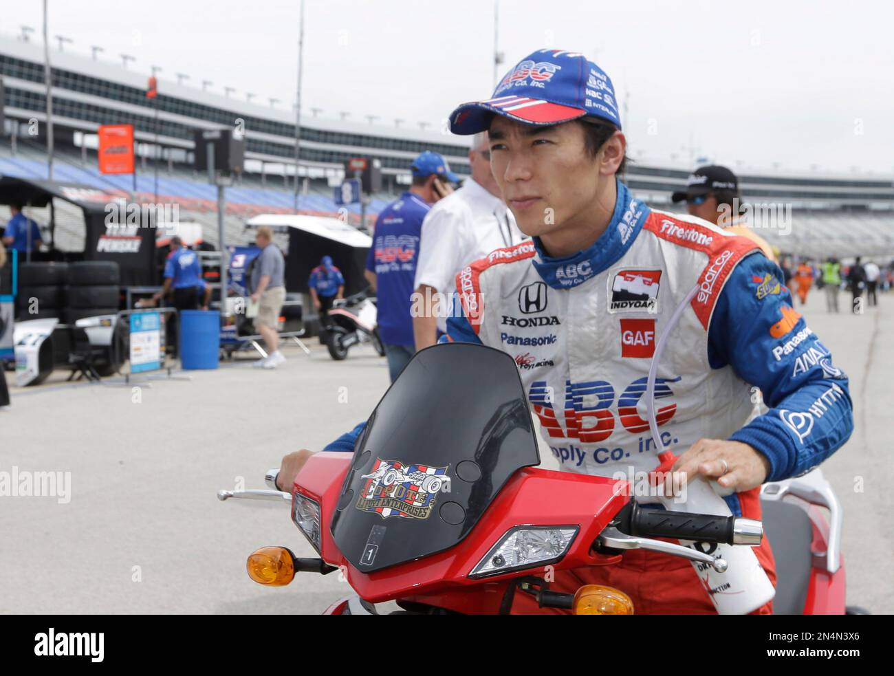 Takuma Sato, of Japan, drives a scooter in the pits before the IndyCar ...