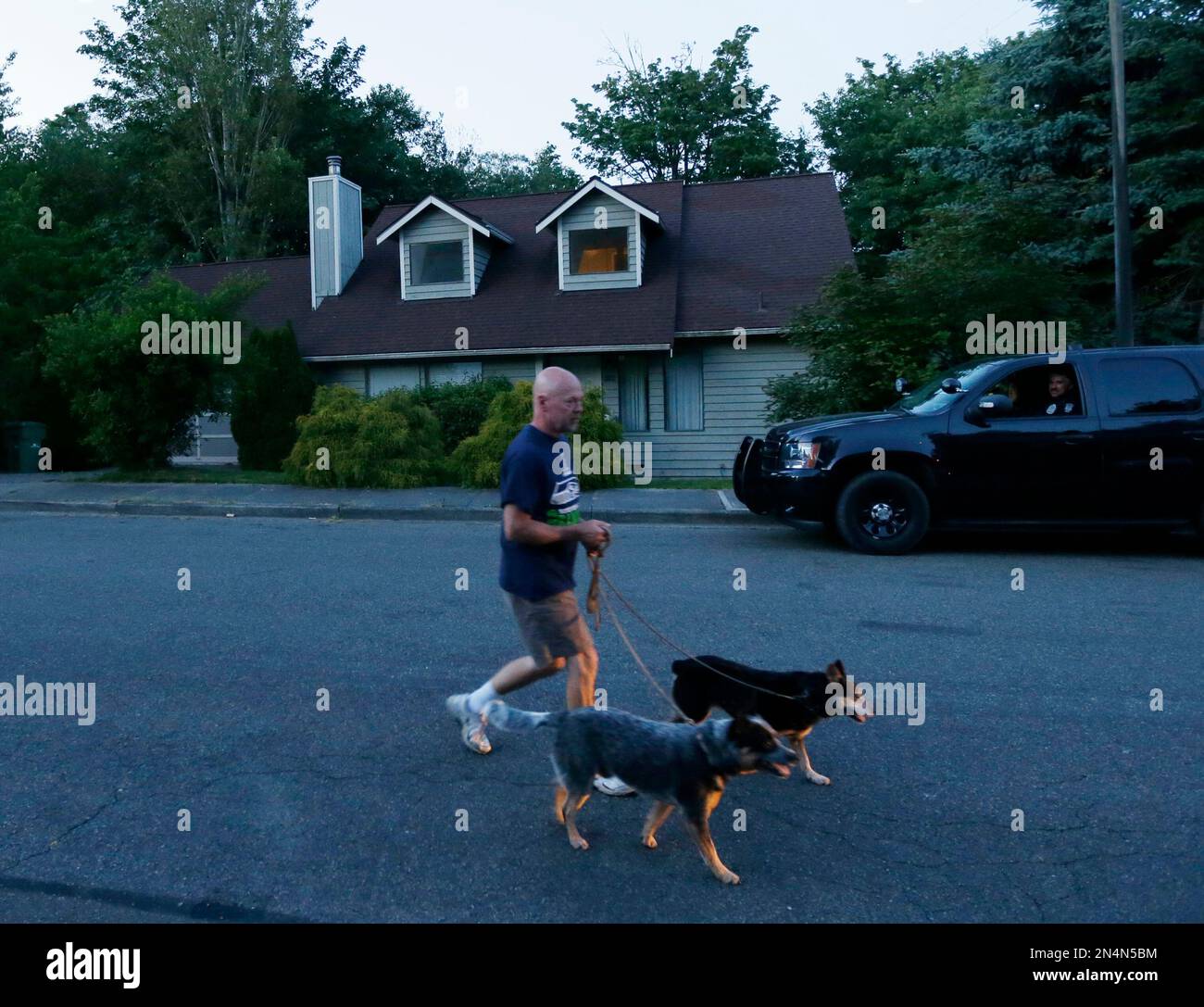 A man walks his dogs past a home believed to be tied to Aaron R. Ybarra ...