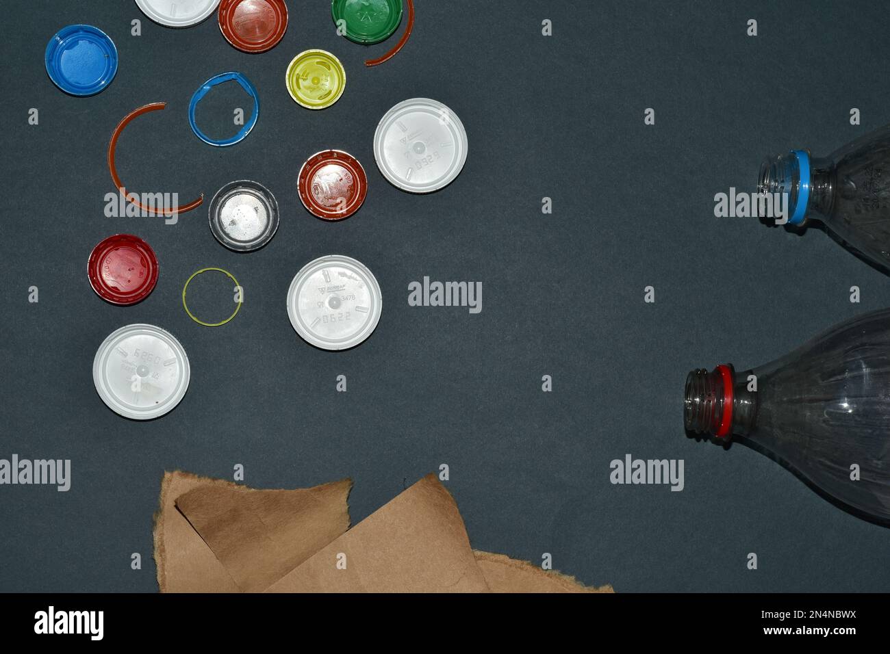 Plastic bottle caps, bottles and cardboard on a gray background ...