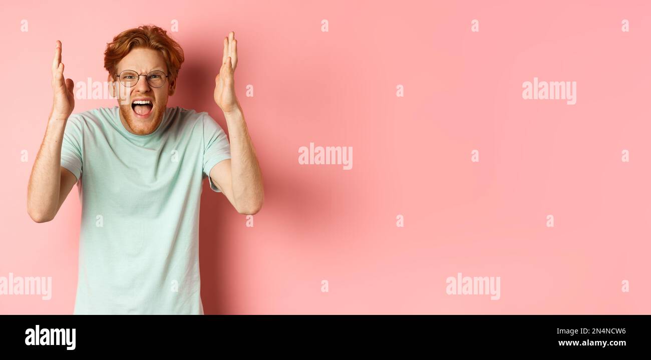 Angry redhead guy in glasses shouting, frowning and shaking hands with ...
